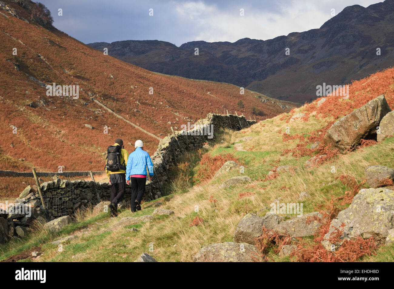 Two people walking on Cumbria Way path through Langstrath Valley in the ...