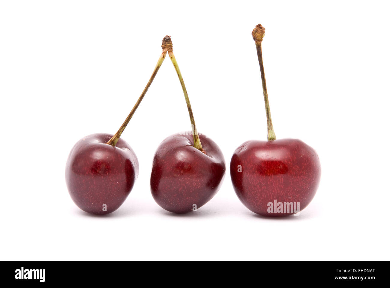 Three red cherries on a white background Stock Photo - Alamy
