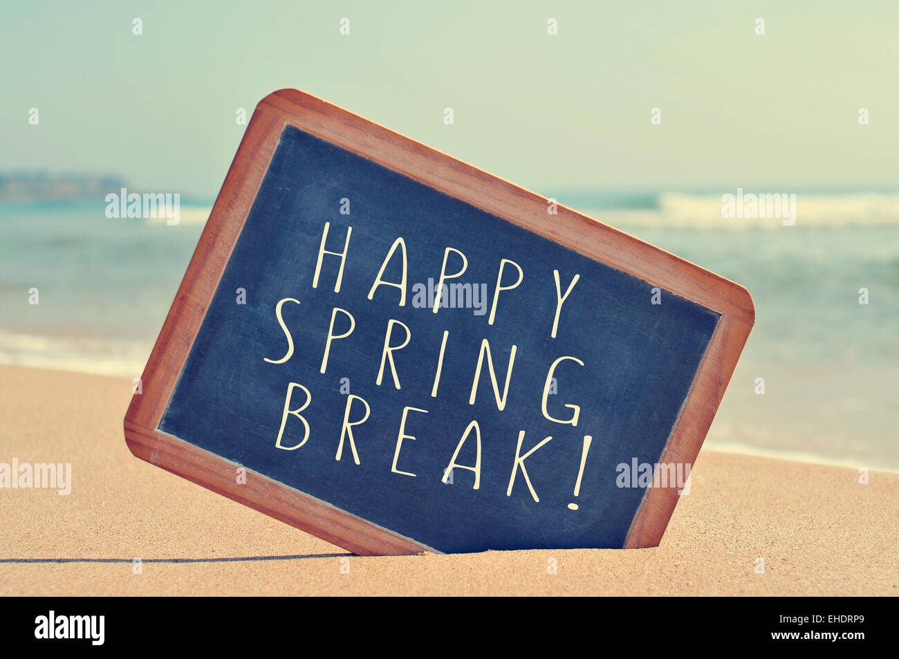 the text happy spring break written in a blackboard on the sand of a ...