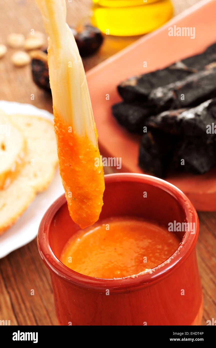 closeup of a barbecued calcot, sweet onion, dipped in romesco sauce ...