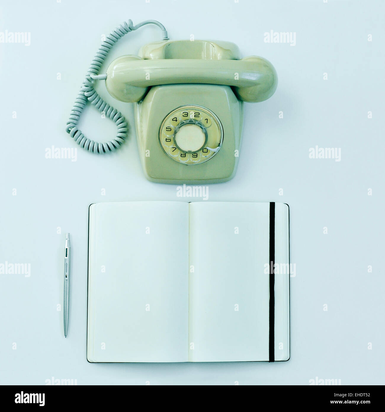 high-angle shot of a rotary telephone, a pen and a blank notepad on a ...