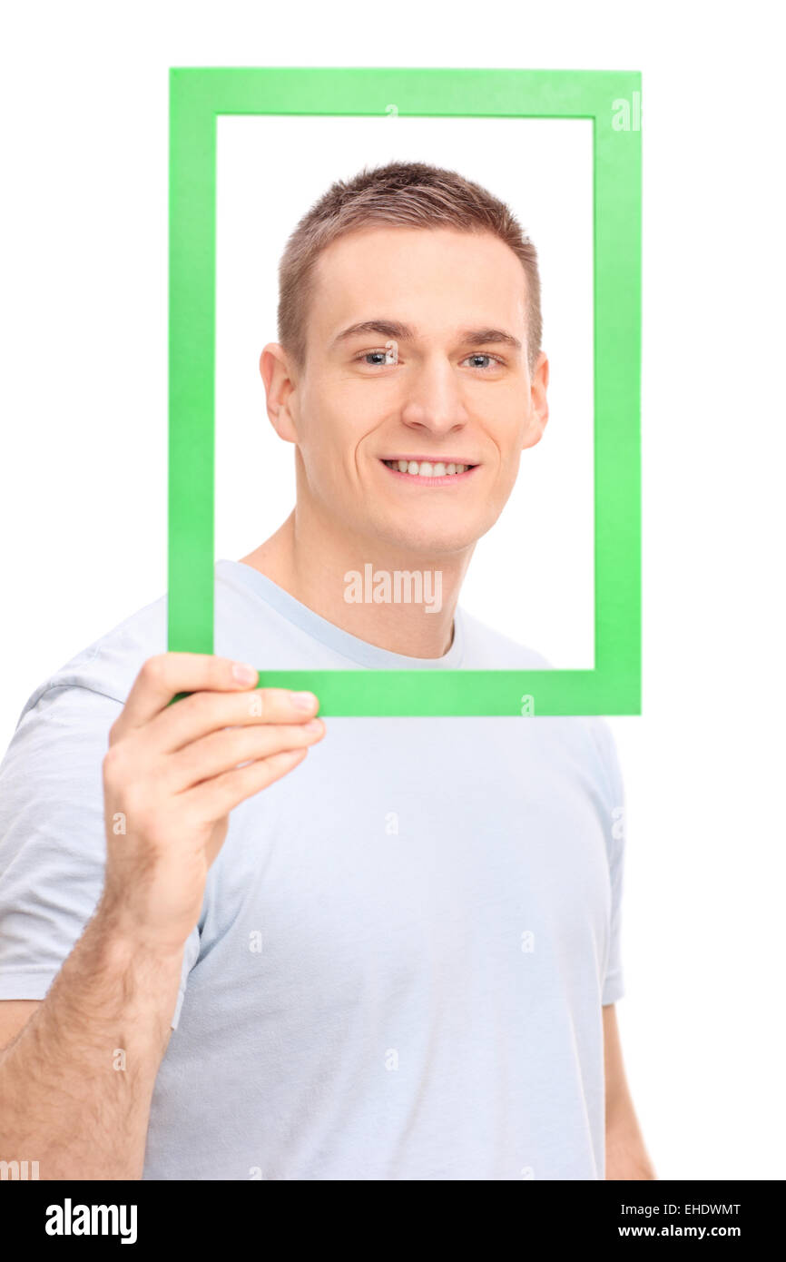 Young man posing behind a green picture frame isolated on white ...