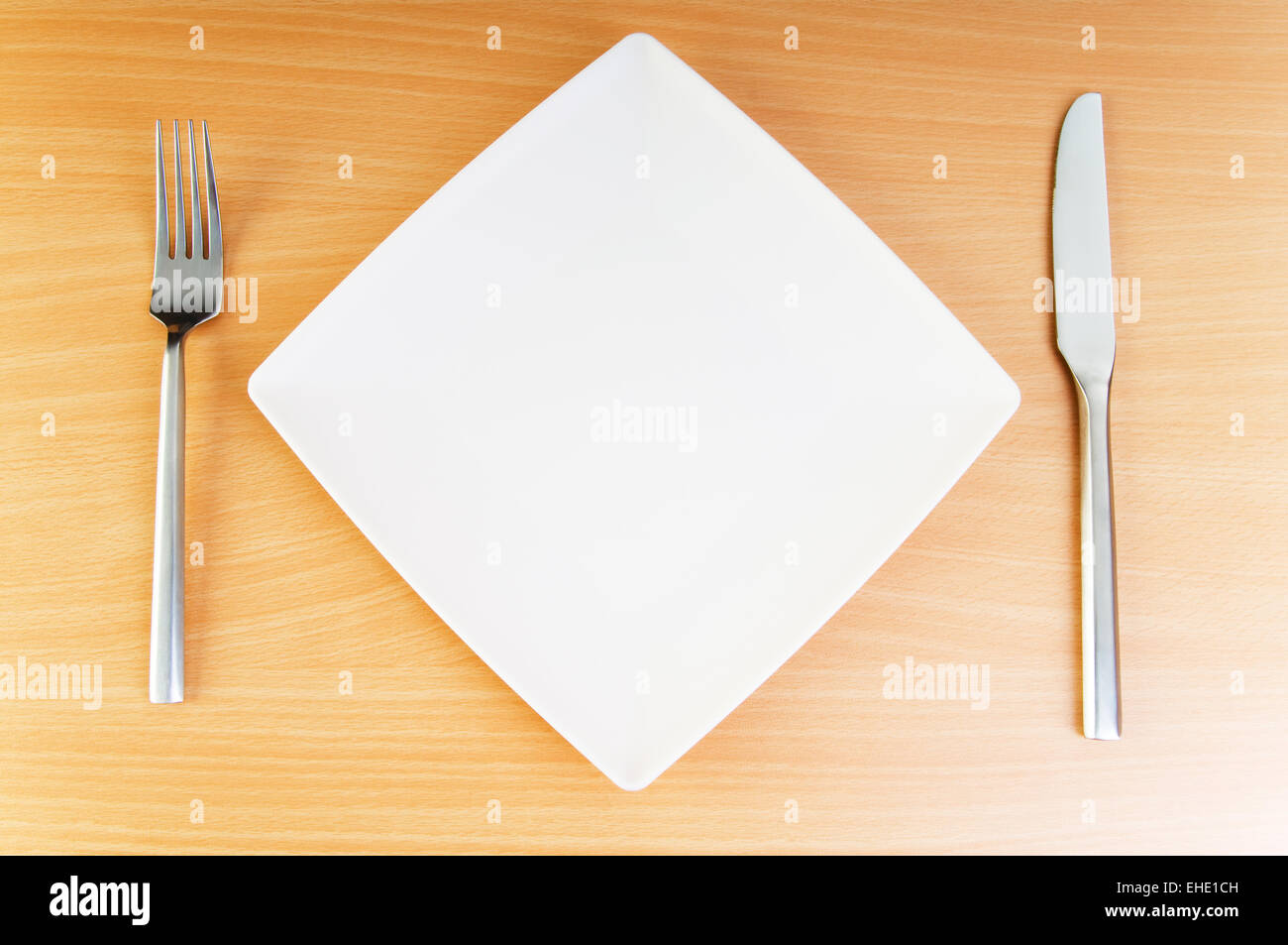 Plate with utensils on wooden table Stock Photo - Alamy