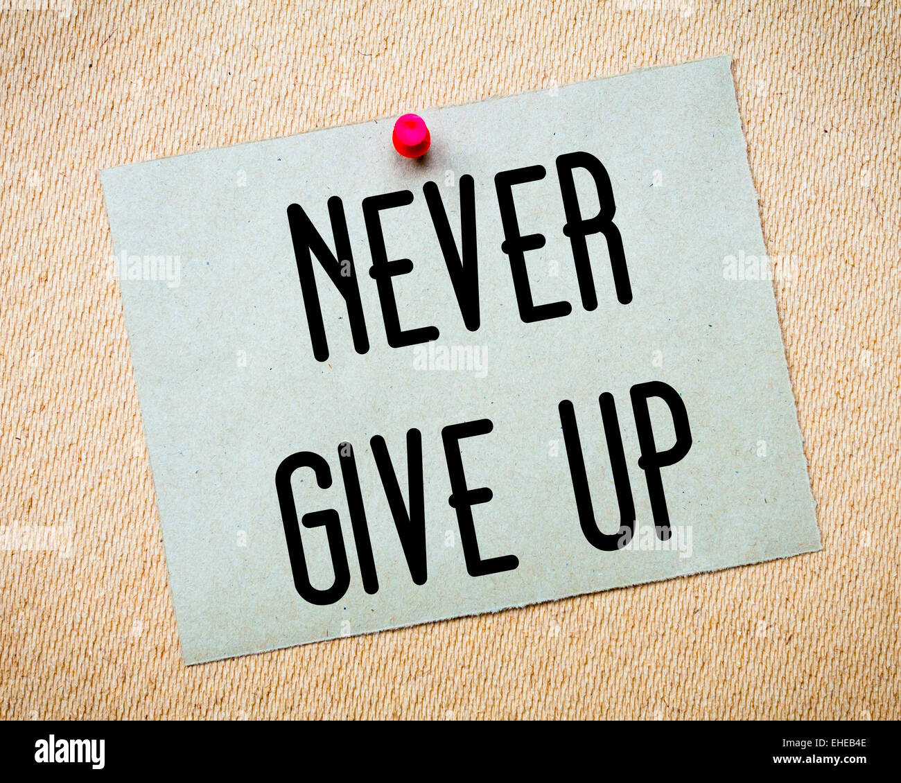 Recycled paper note pinned on cork board. Never Give Up Message ...