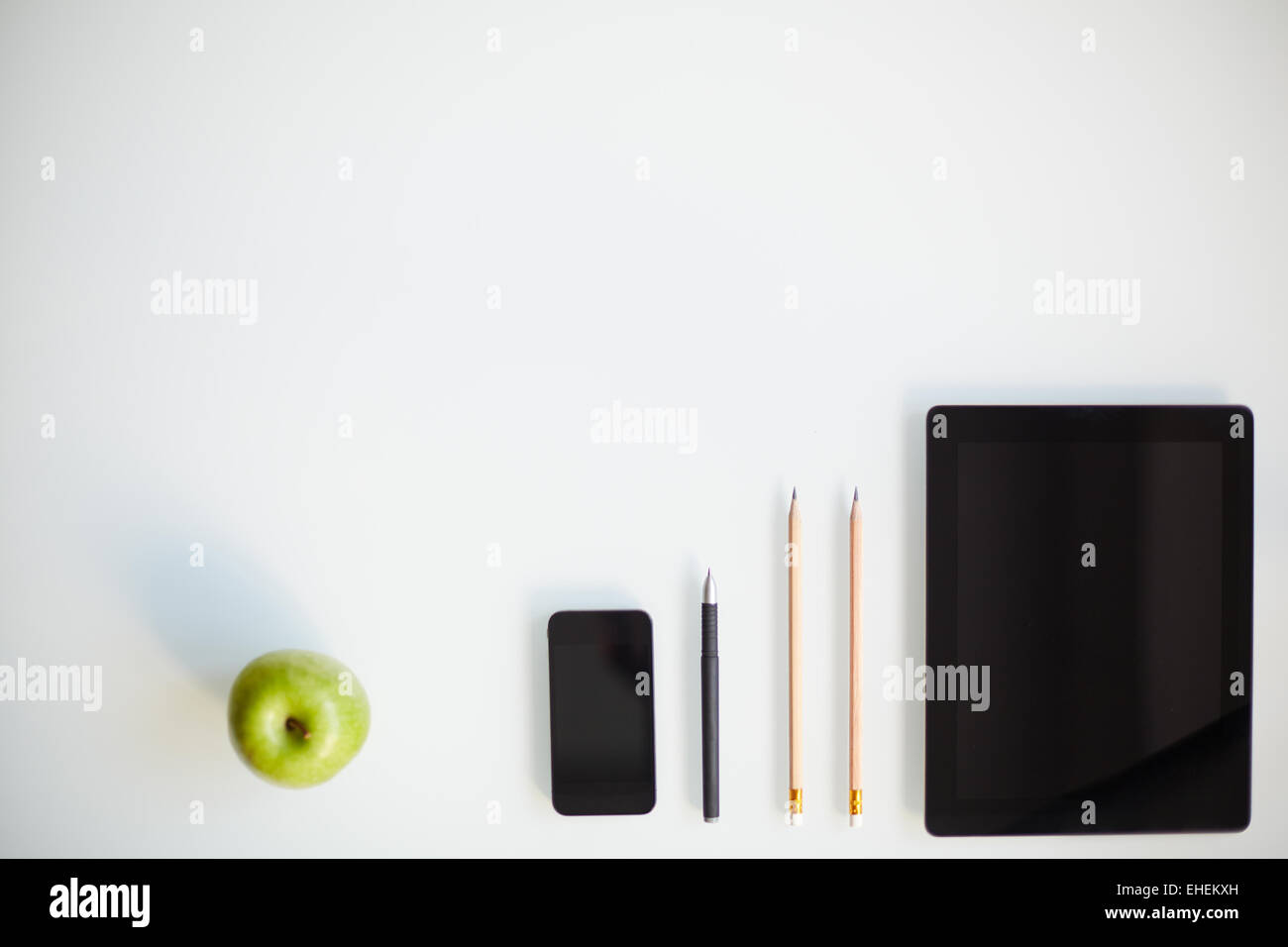 Writing instruments, smartphone, touchpad and apple Stock Photo - Alamy
