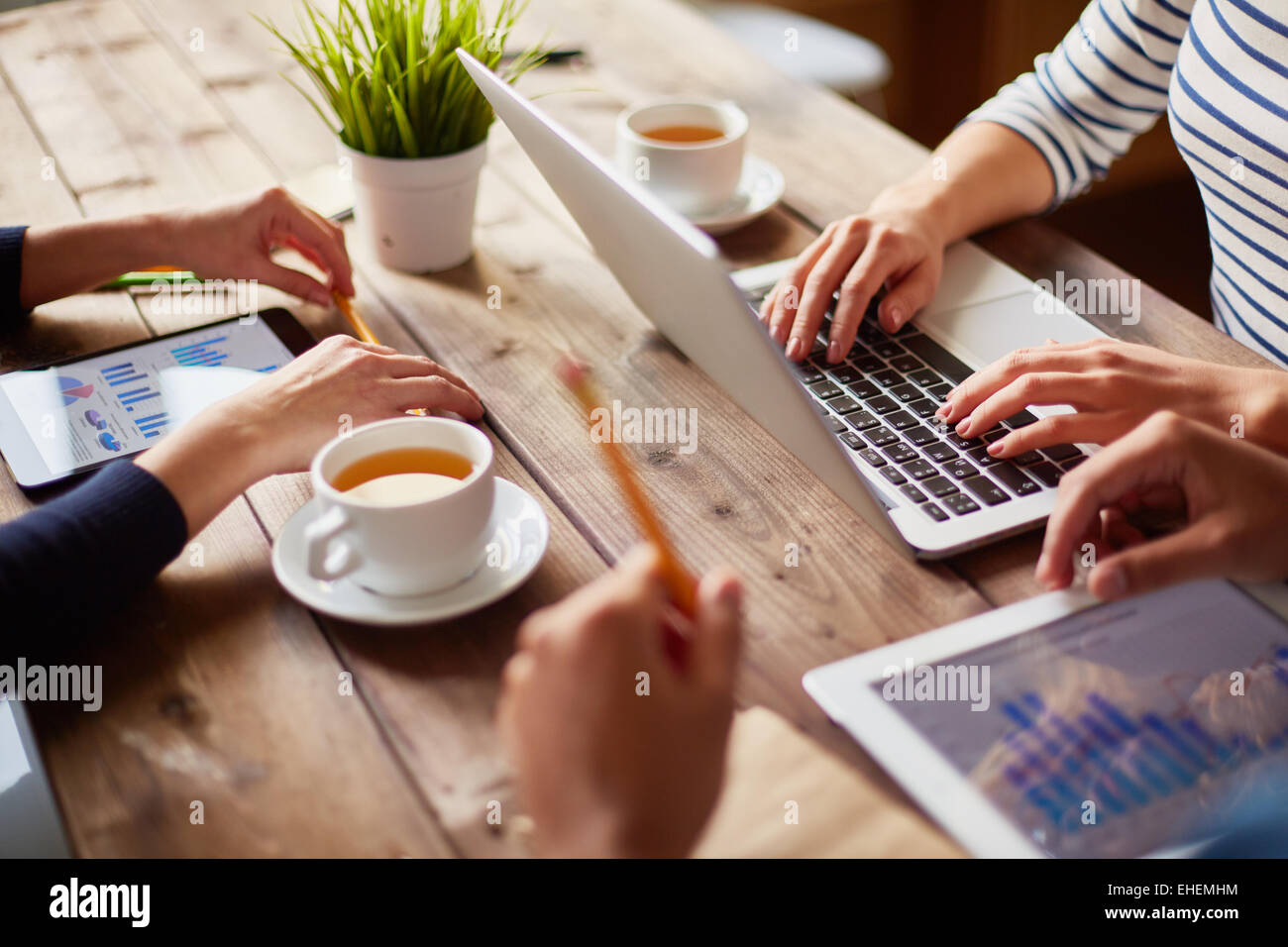 People using different devices at one table Stock Photo - Alamy