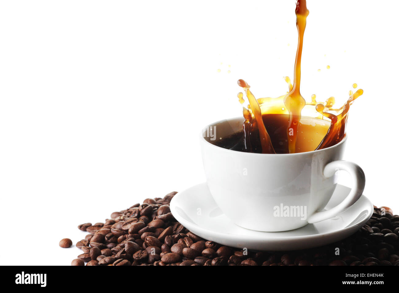 Pouring coffee with splash in cup on coffee beans isolated on white ...