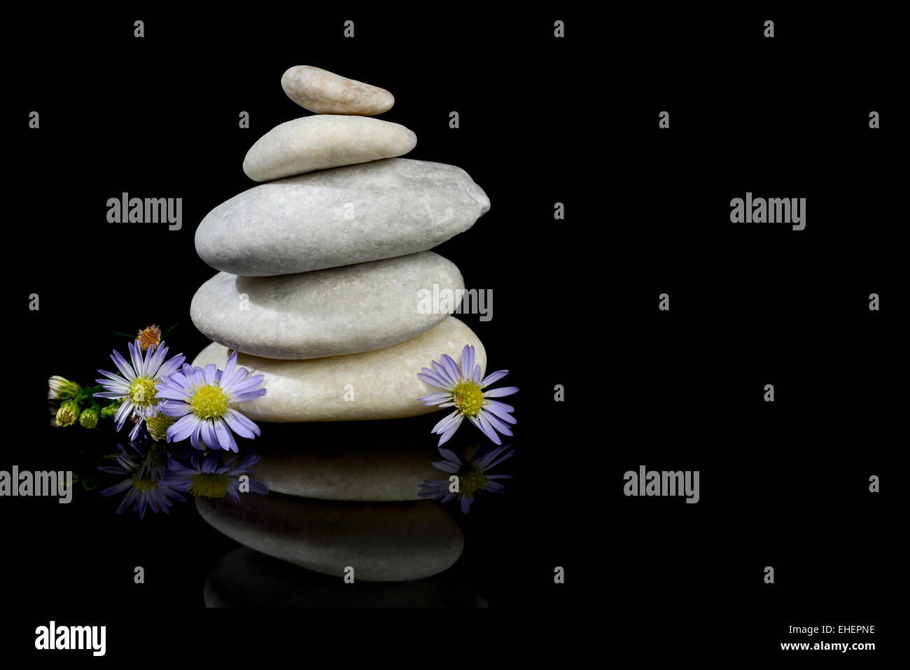 Flower and stones stacked isolated with black background reflection ...