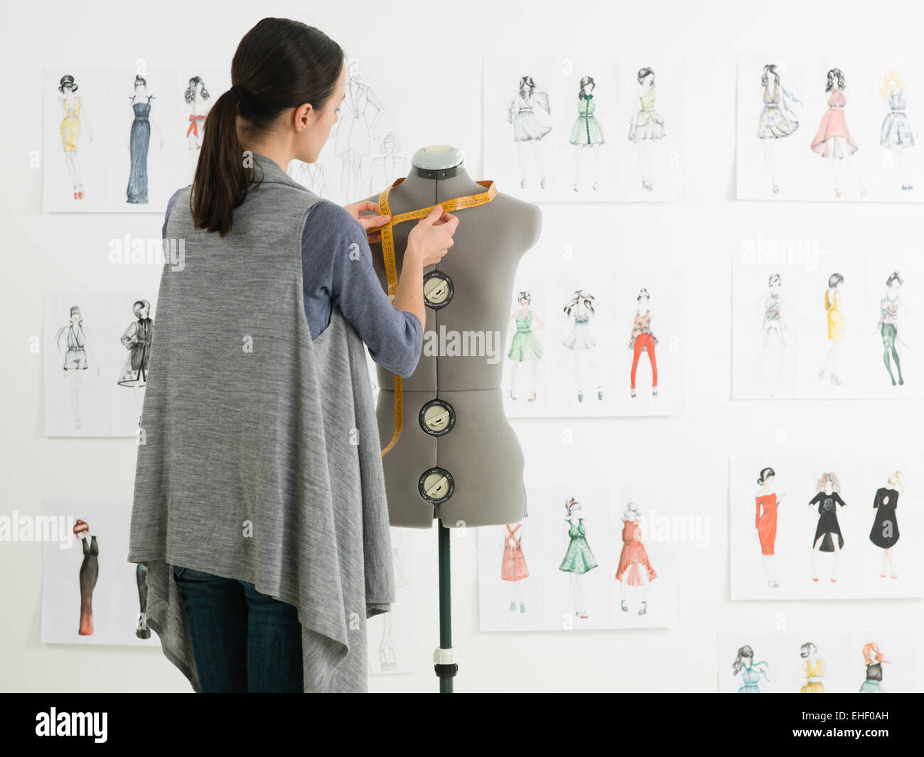 young caucasian female fashion designer taking measurements on ...