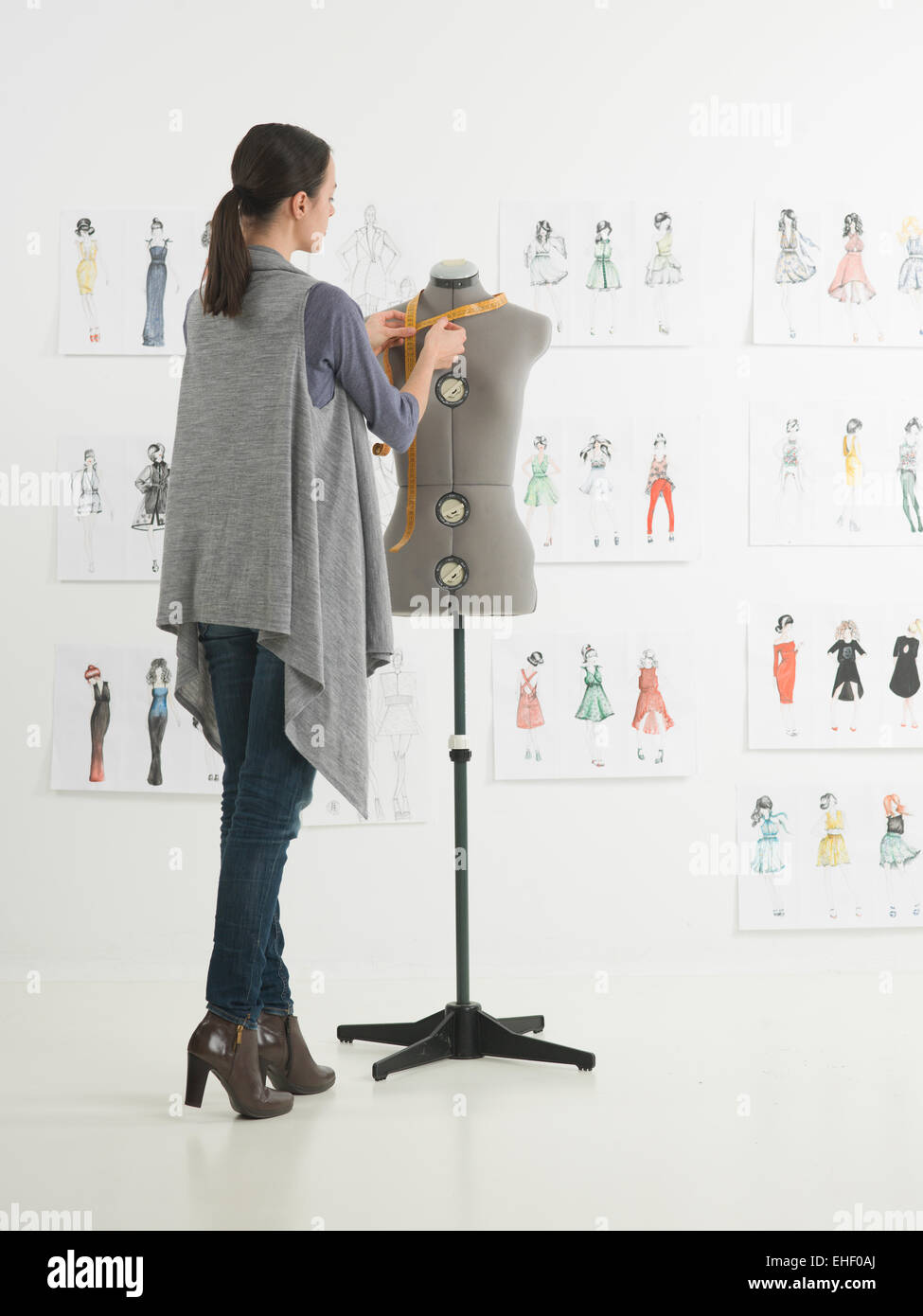 young caucasian female fashion designer taking measurements on ...