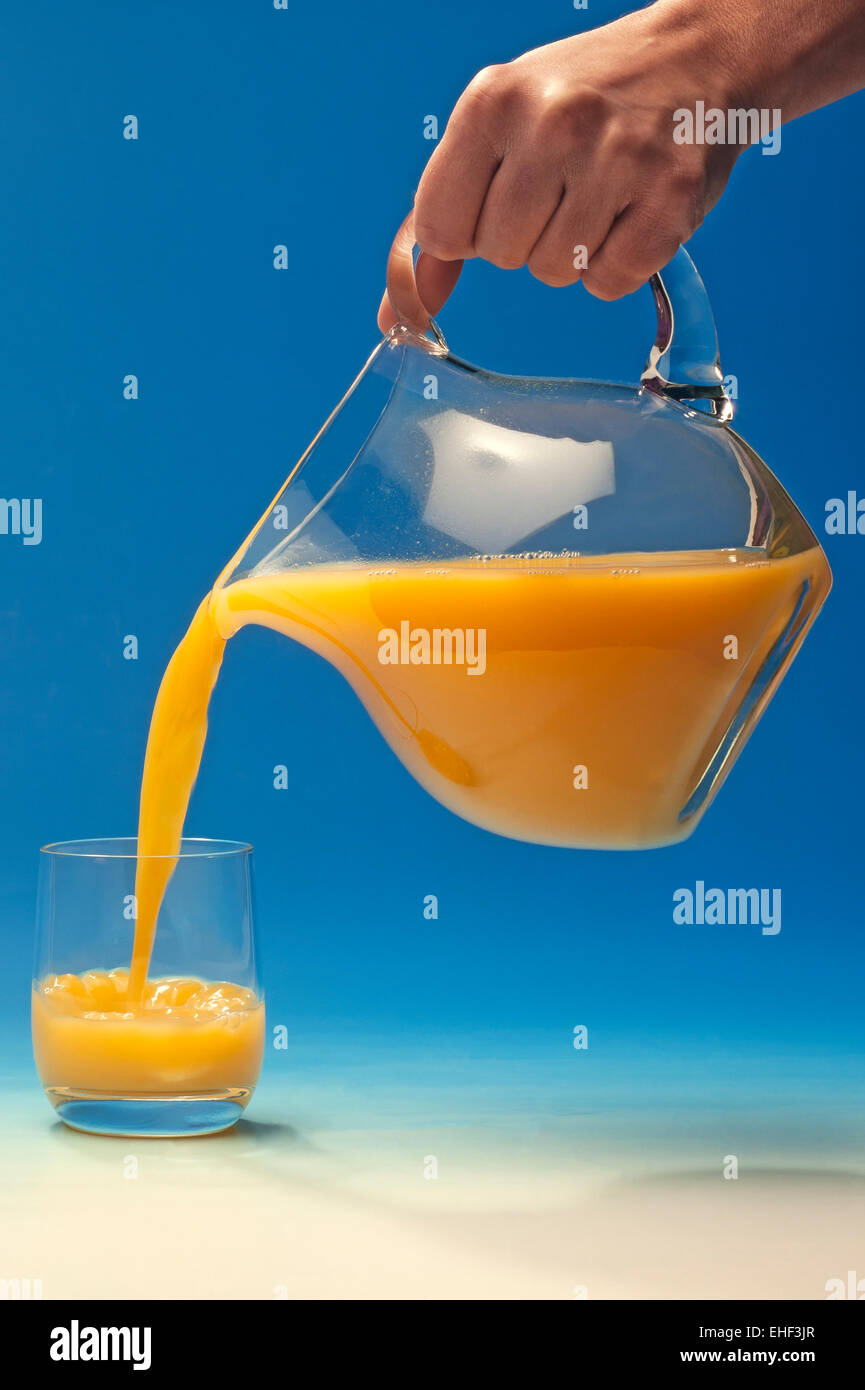 Hand pouring orange juice out of a jug into a glass Stock Photo - Alamy
