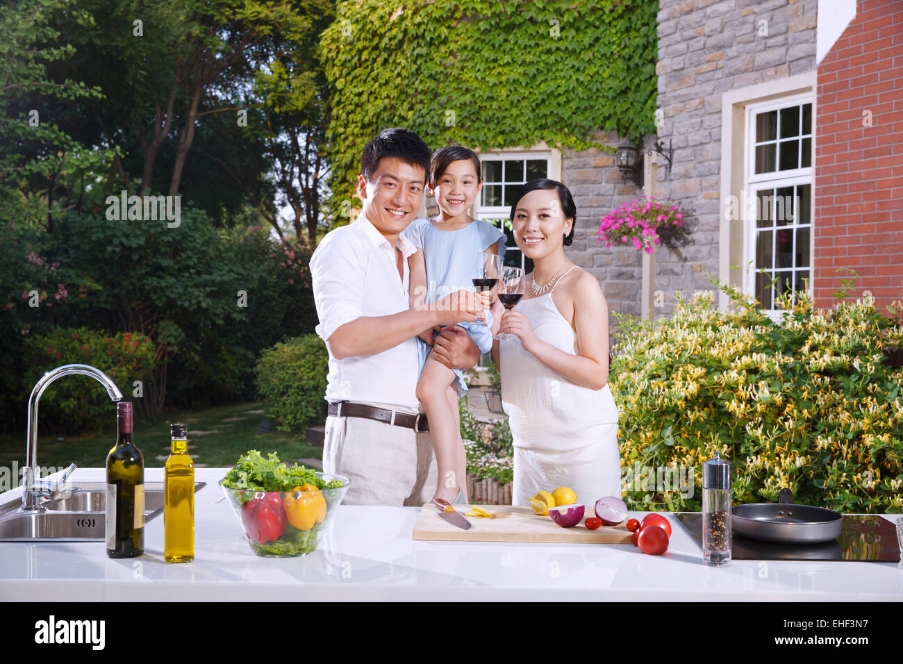 Parents holding a red wine and daughter outside the kitchen Stock Photo ...