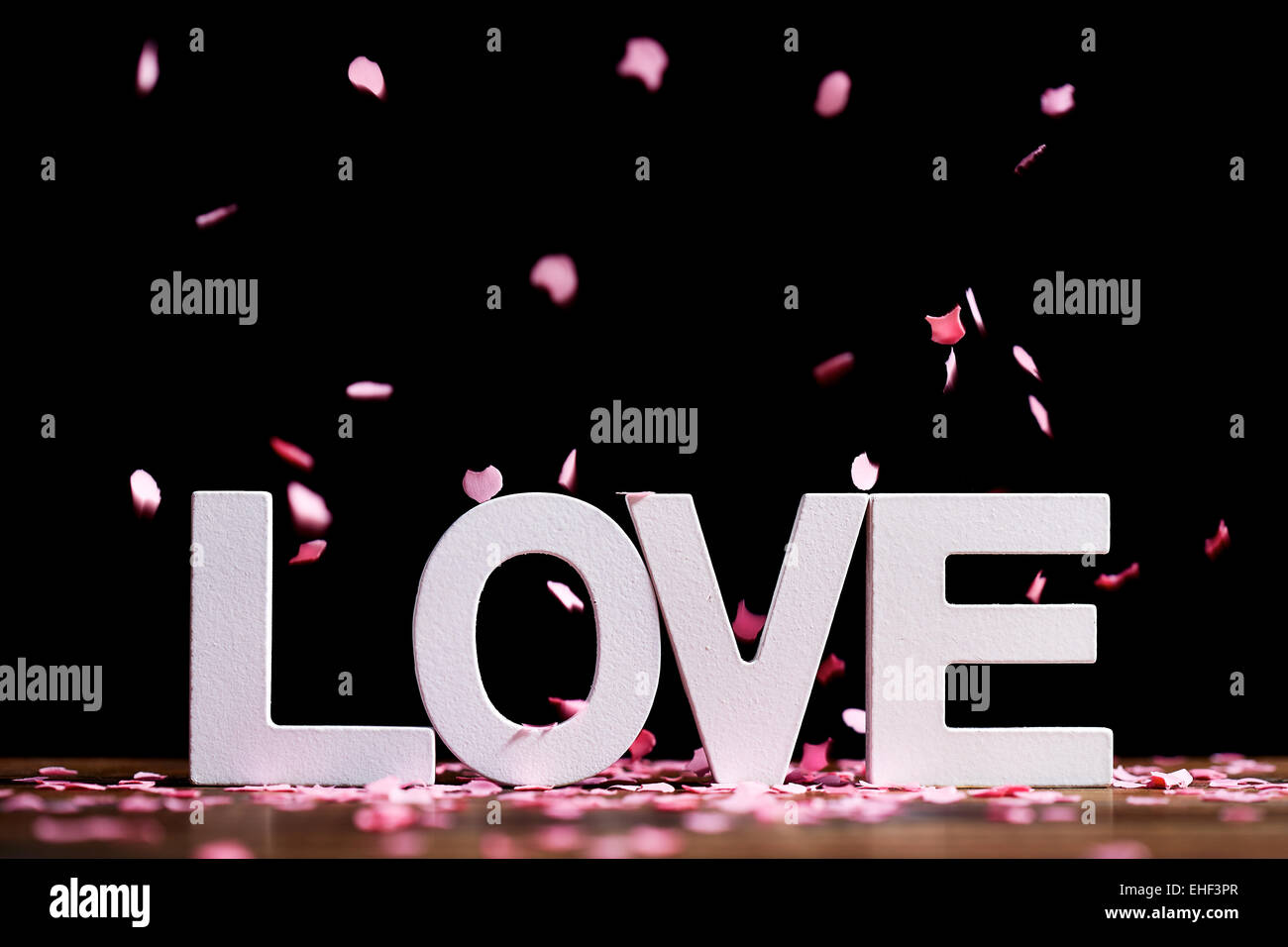 Falling pink confetti on love word written in white letters Stock Photo ...
