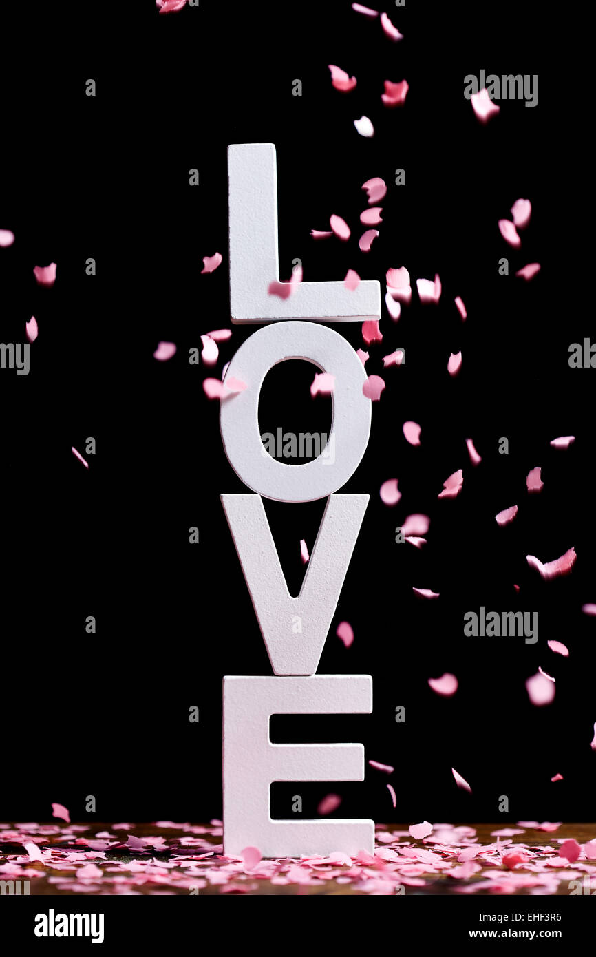 Falling pink confetti on love word written in white letters Stock Photo ...