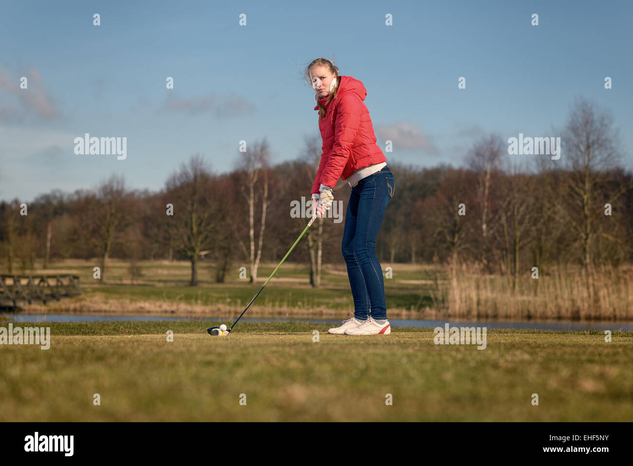 Woman teeing of on a golf course standing in the tee box in front of a ...