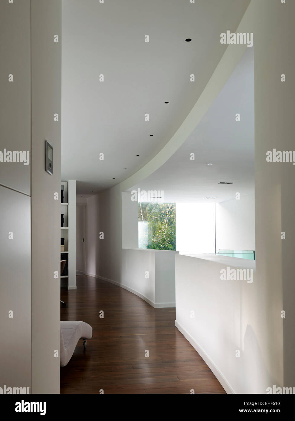 Curved internal corridor with wooden floor and light fittings in ...