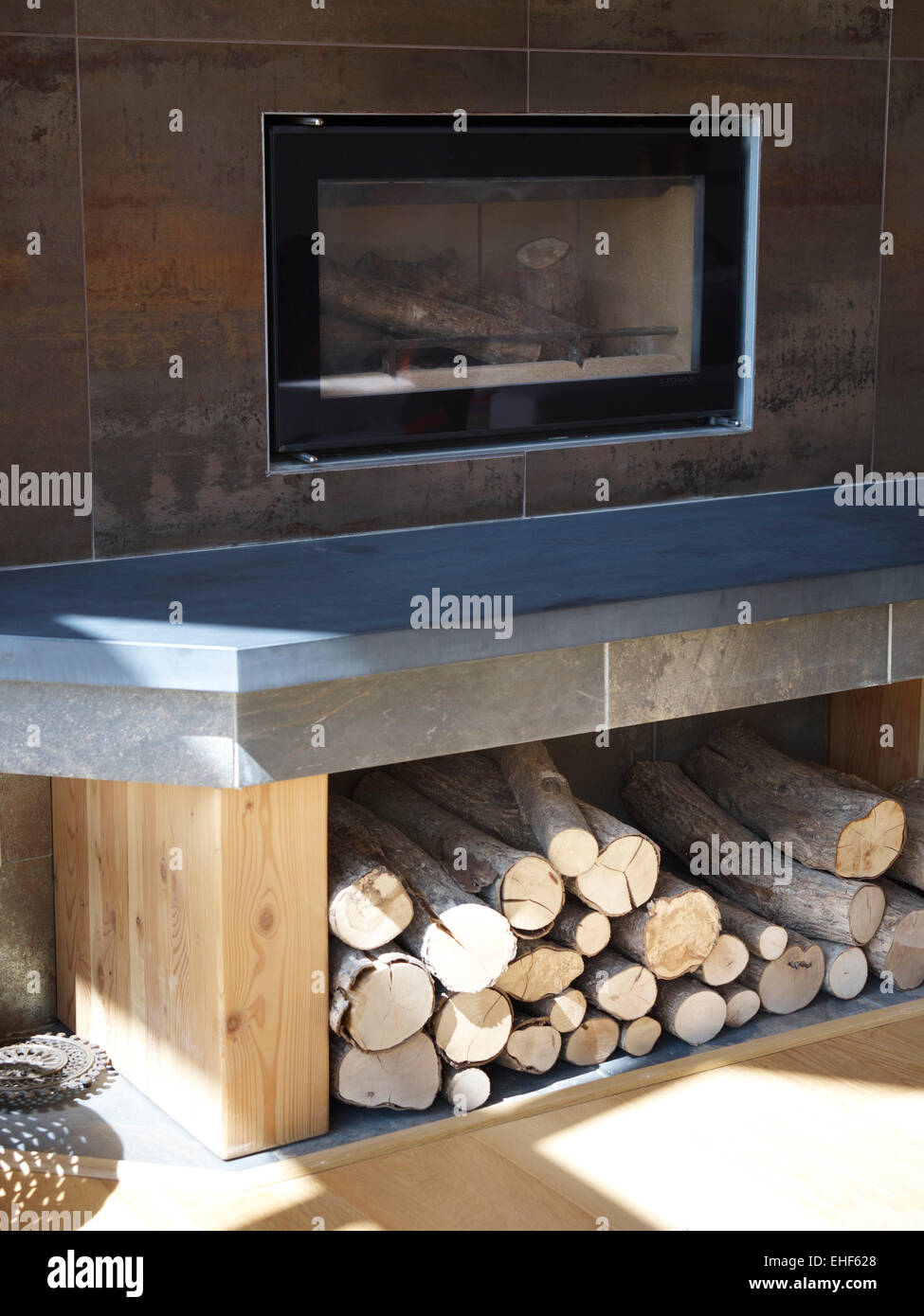 Glass front of log fire with log hold in lounge of Kusala home, UK ...