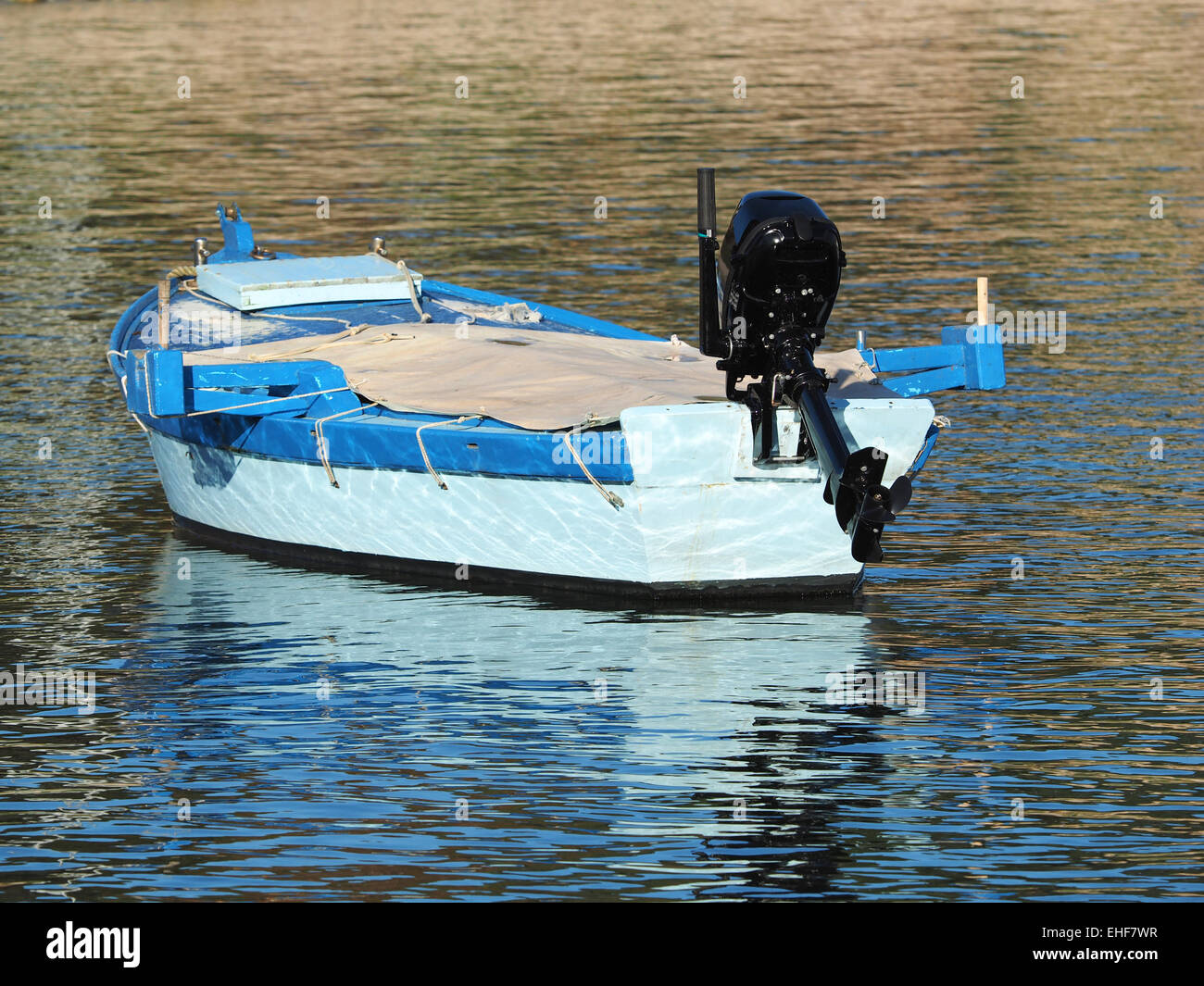 small wooden barge boat with outboard engine floats through blue lagoon ...