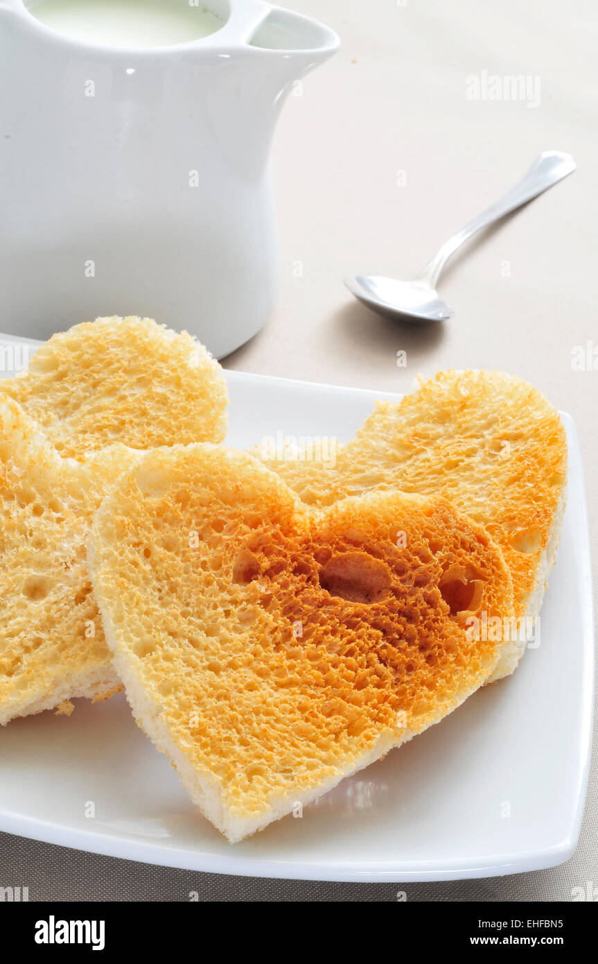 a plate with some heart-shaped toasts served on a set table and a milk ...