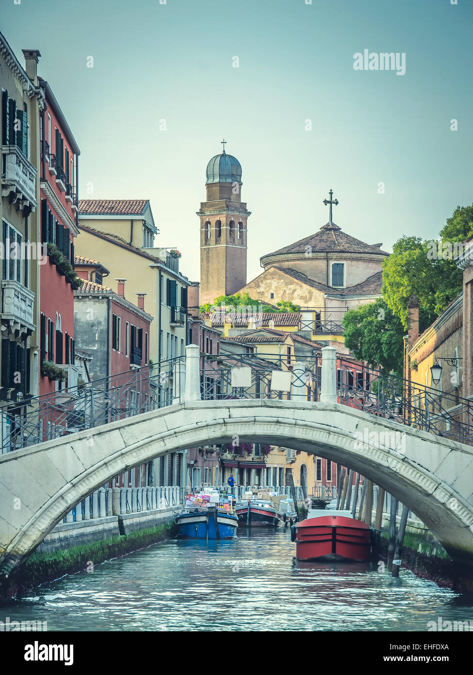 Venice cityscape, small bridge, narrow water canal with boats, church ...