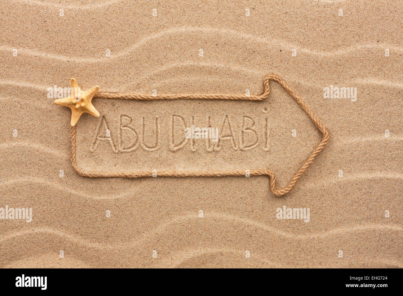 Arrow made of rope and sea shells with the word Abu dhabi on the sand ...