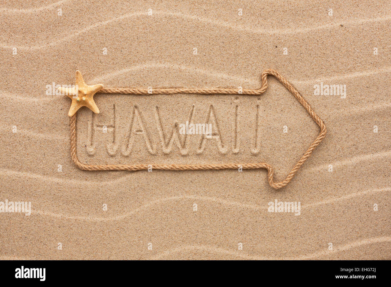 Arrow made of rope and sea shells with the word Hawaii on the sand, as ...