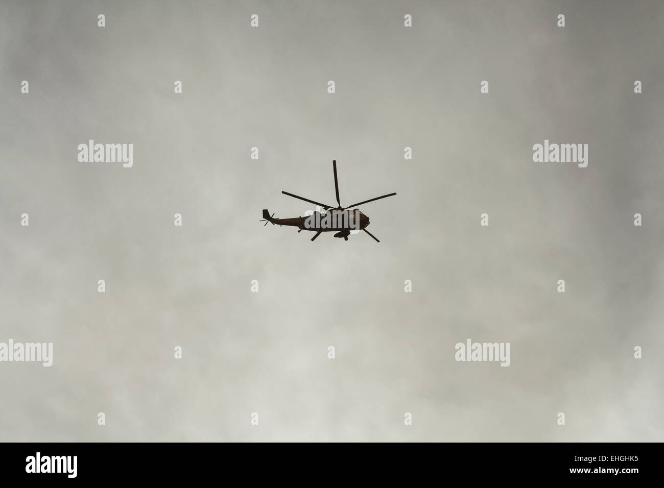 Dark helicopter flying in cloudy sky Stock Photo - Alamy