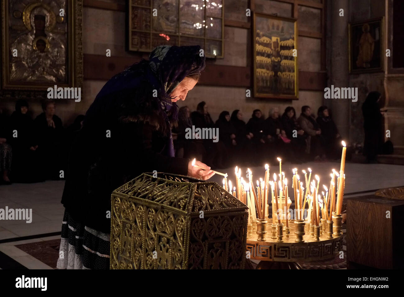 An Eastern Orthodox Christian worshiper lights candles during a mass ...