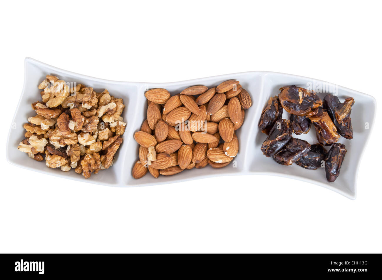 Walnuts almonds and dates in a white dish isolated on white background ...