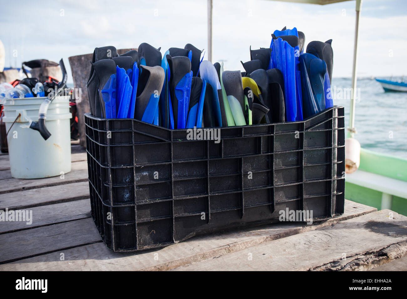 Diving equipment, set of blue flippers in plastic box on wooden pier ...