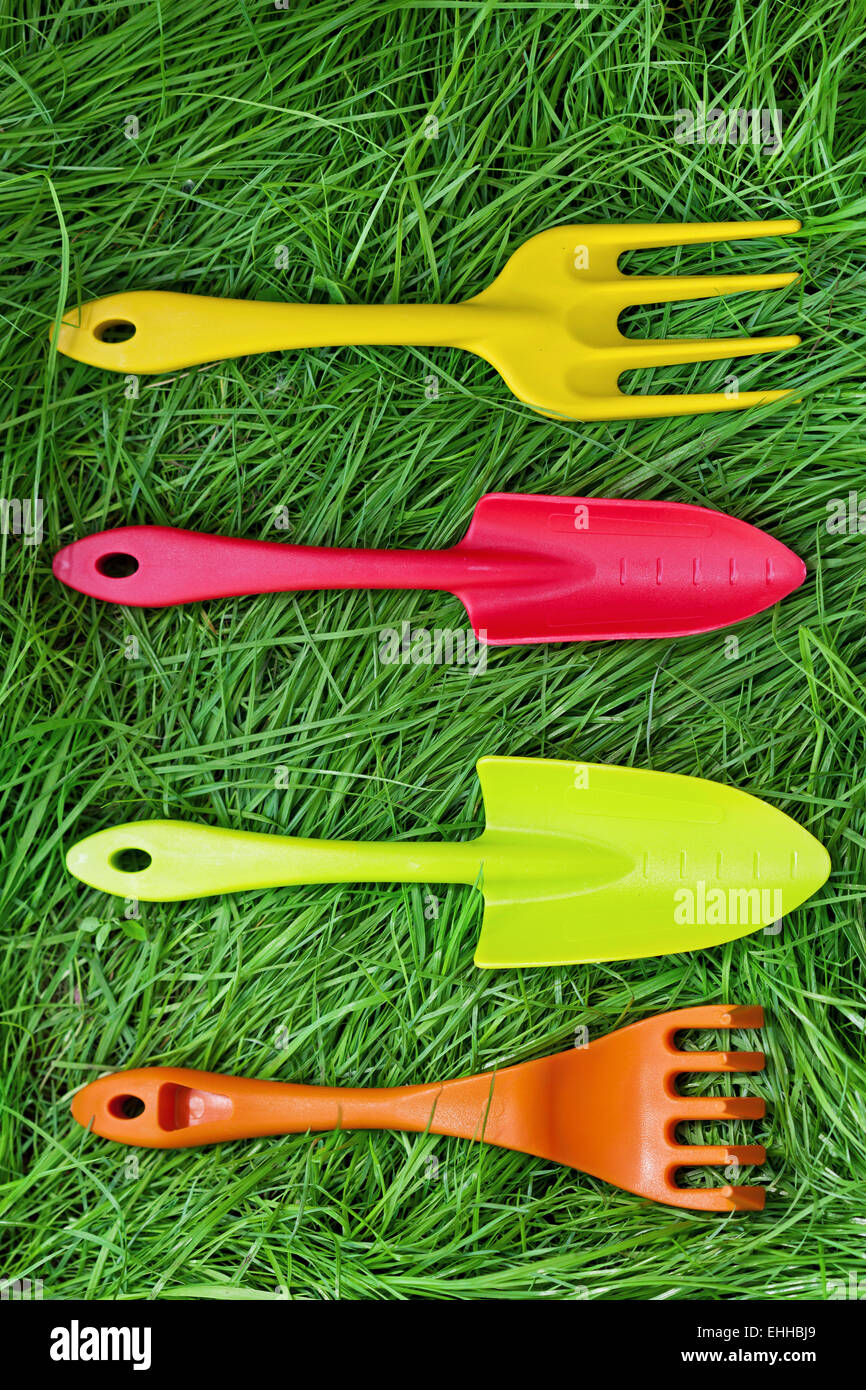 Set of gardening tools on green grass background. Plastic mini shovels ...
