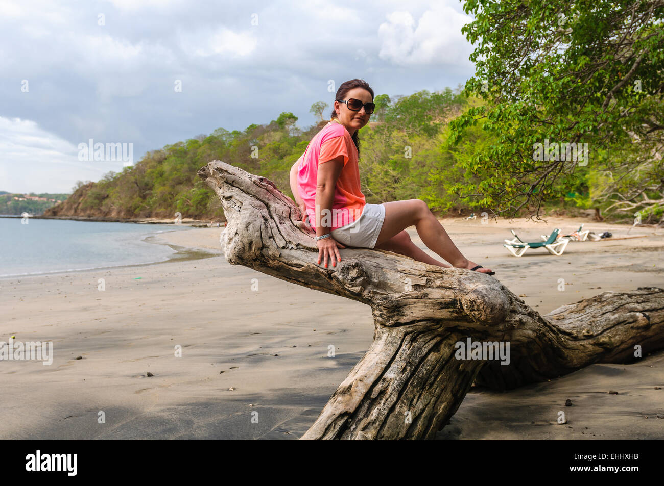 happy woman sitting on a stump thrown by the waves Stock Photo - Alamy
