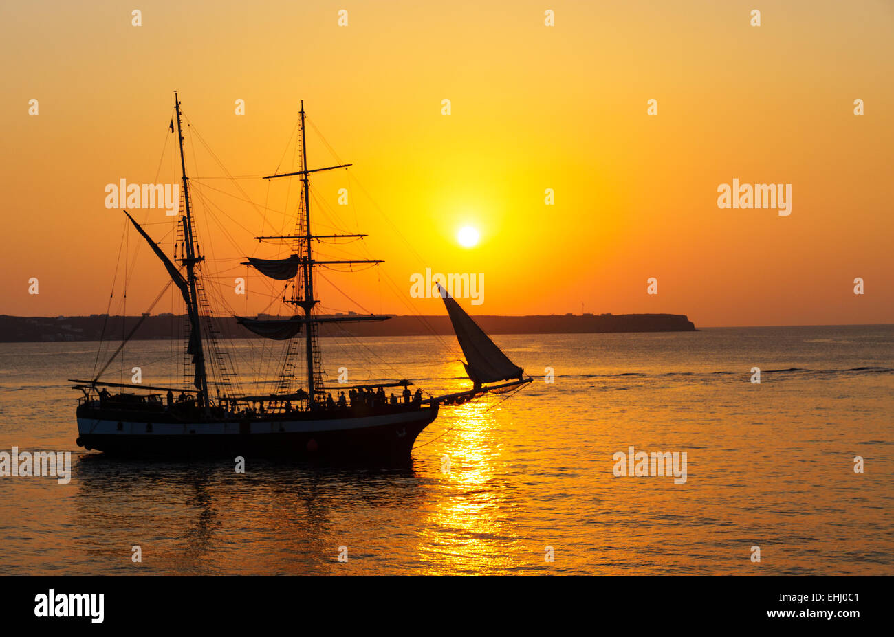 Sunset with sailing ship Stock Photo - Alamy