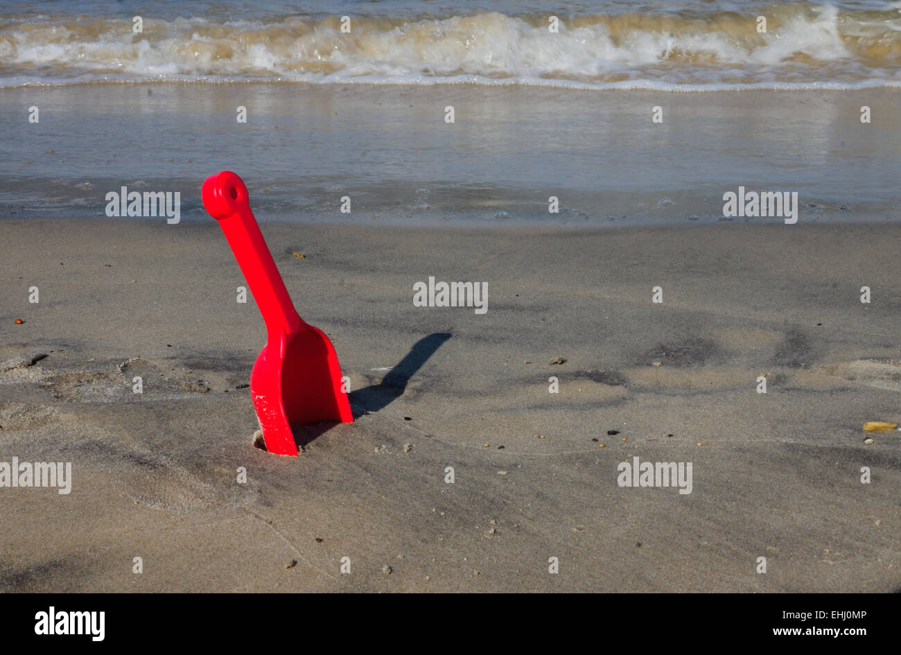 Red shovel at the beach Stock Photo - Alamy