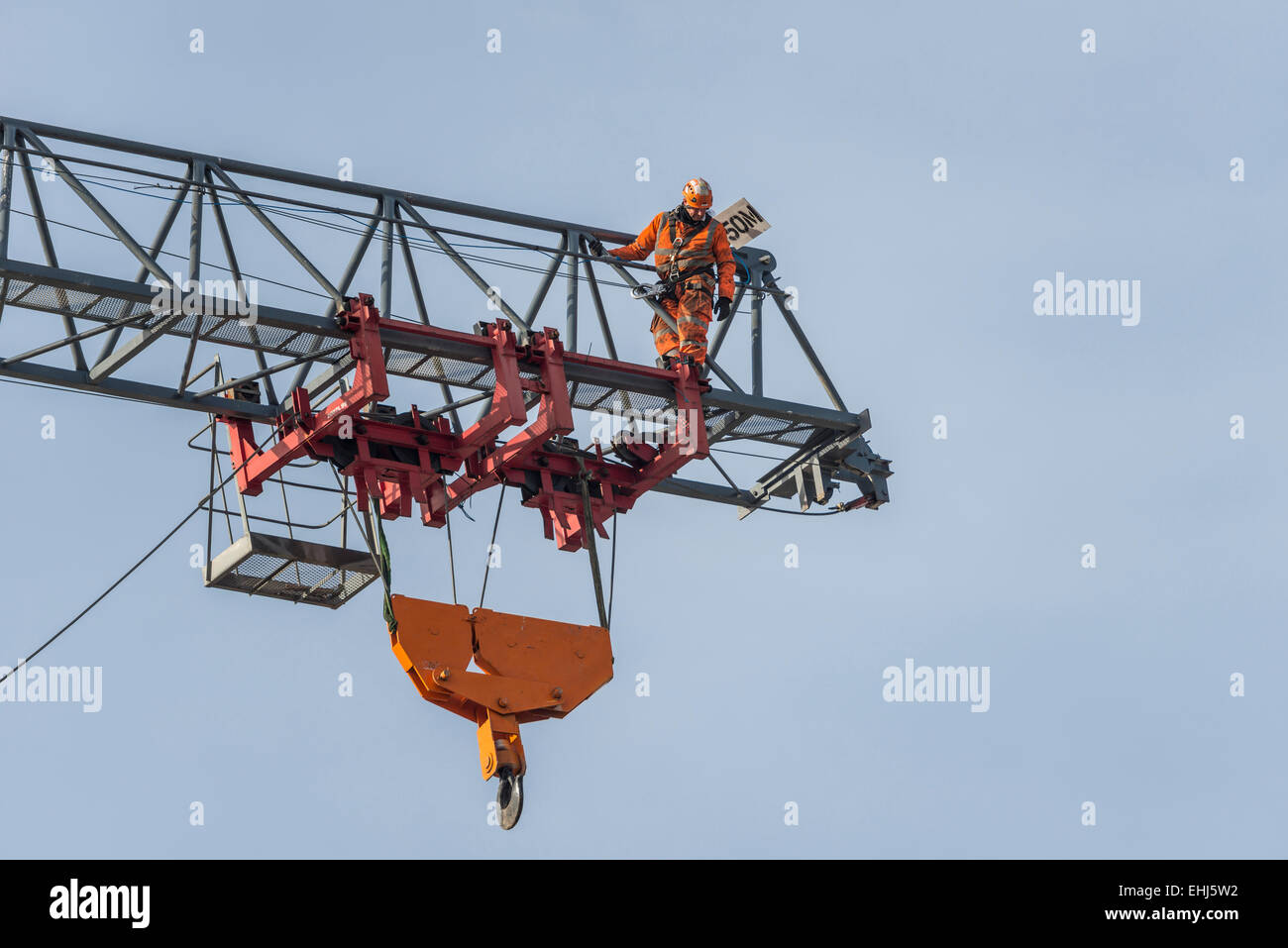 A construction worker on the jib or working arm of a crane on a ...