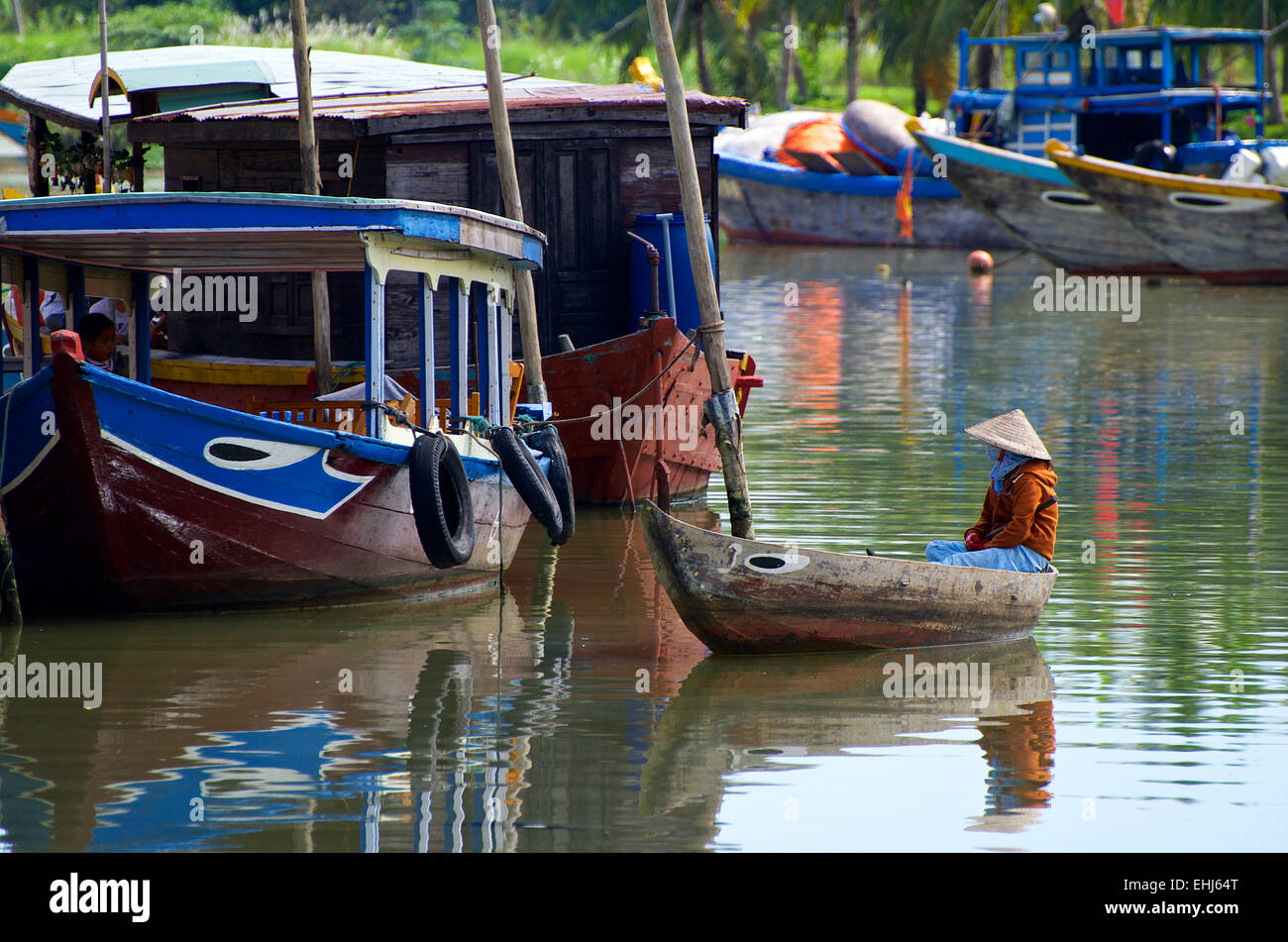 Woman with an asian hat on a small boat among other bigger boats on the ...