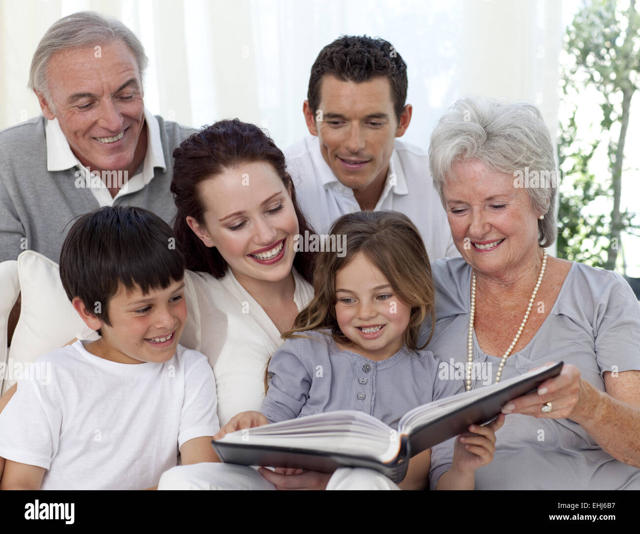 Family reading a book in living-room Stock Photo - Alamy