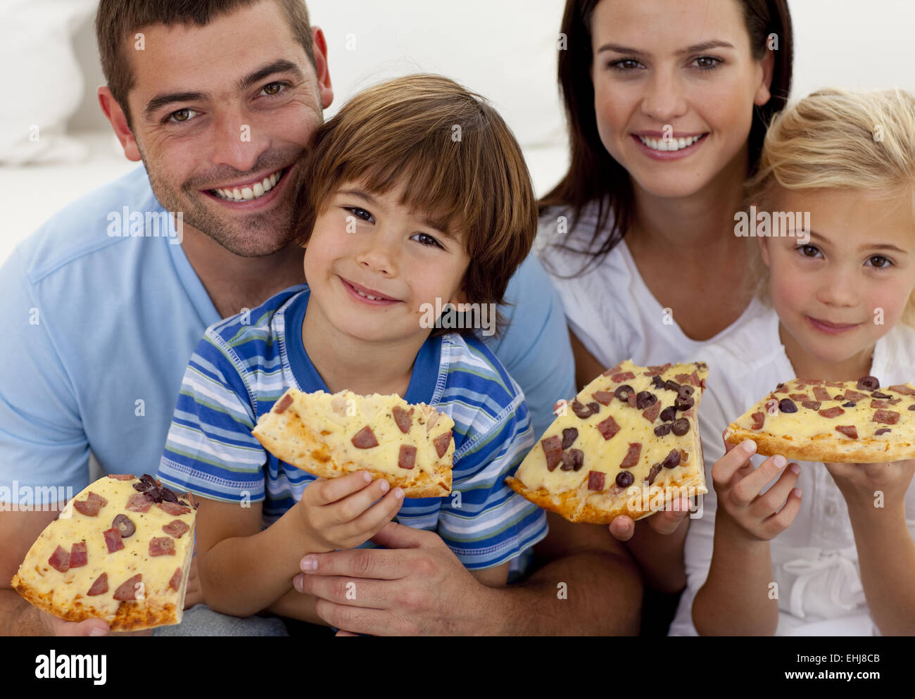 Portrait of family eating pizza on sofa Stock Photo - Alamy