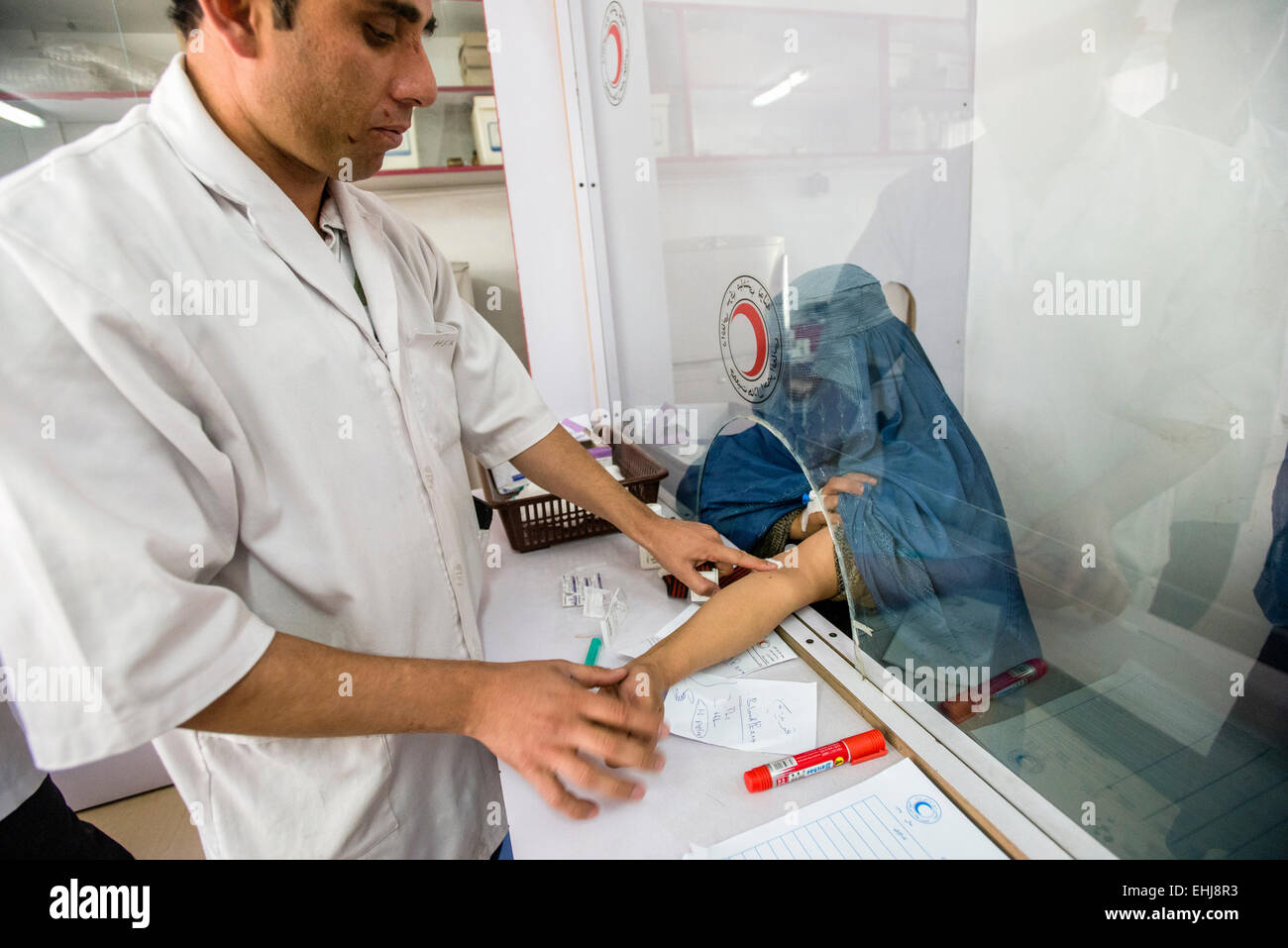 Laboratory manager Hekmatullah Sadat draws blood of woman wearing burka ...