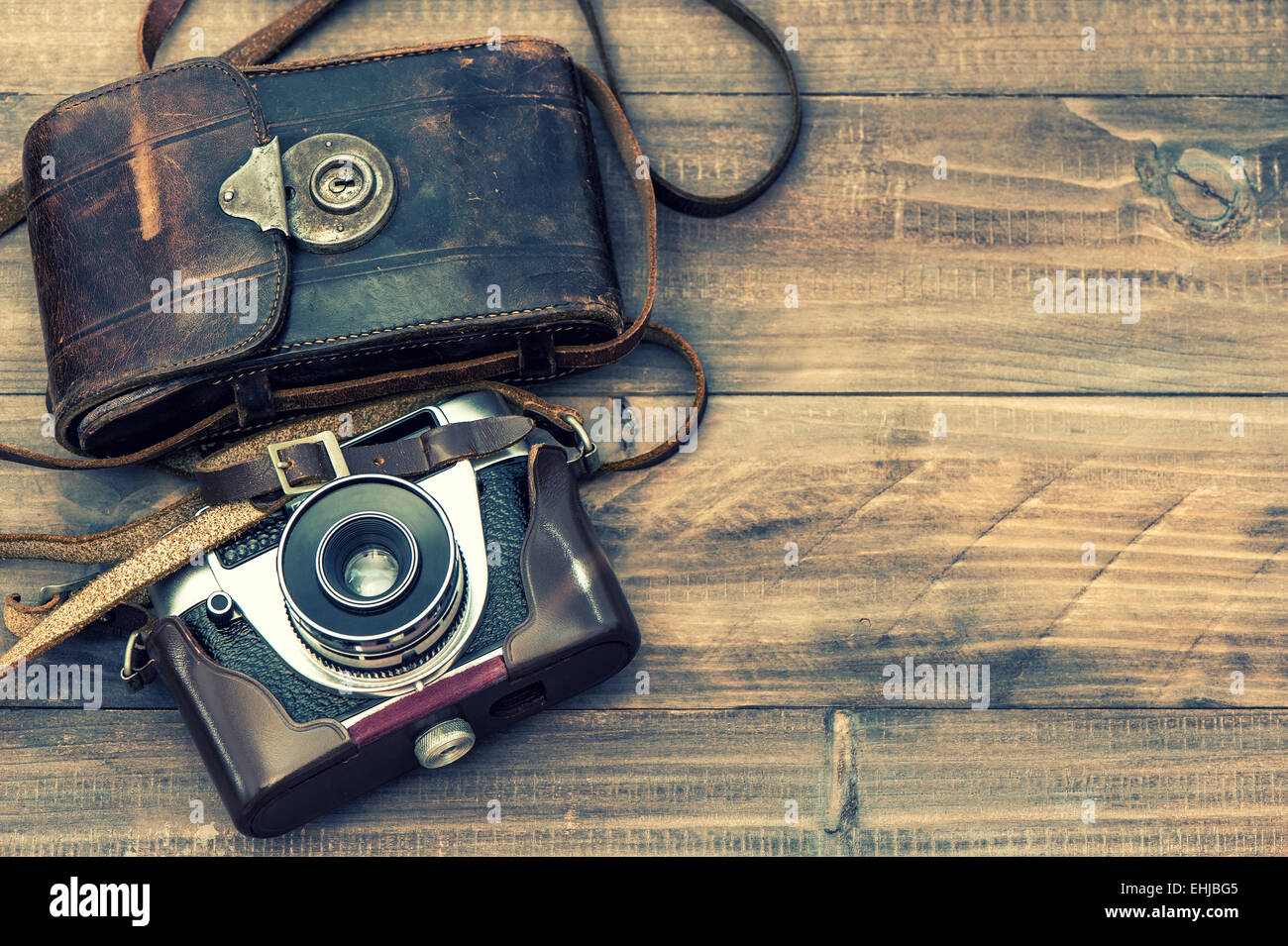 Vintage film photo camera with leather bag on wooden background. Top ...