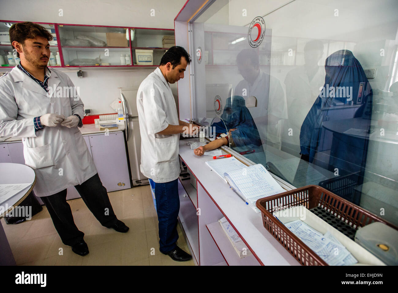 Laboratory manager Hekmatullah Sadat draws blood of woman wearing burka ...