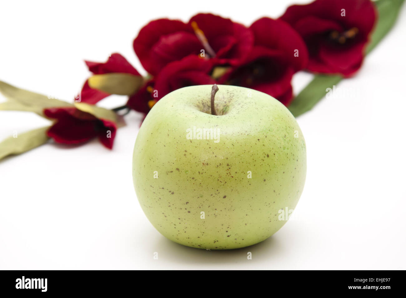 Green apple before red flower Stock Photo - Alamy