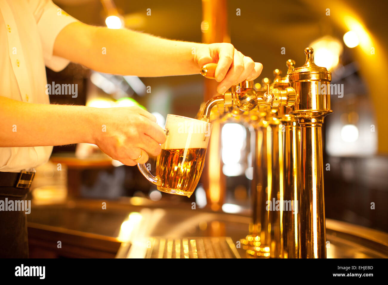 waiter is drafting a beer from a golden spigot Stock Photo - Alamy