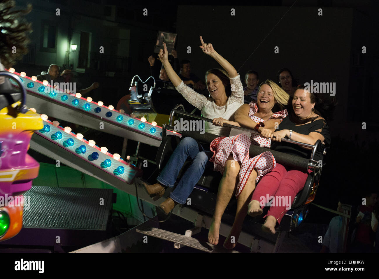 Friends enjoy a fairground ride at the Fiesta de San Miguel in Orgiva ...