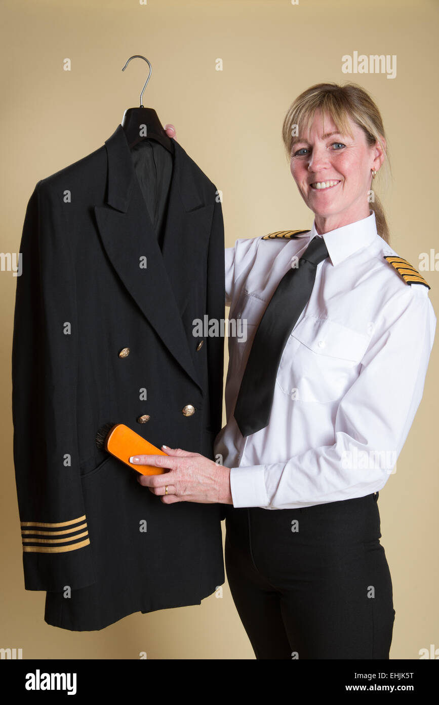 Female airline captain brushing dust from her uniform jacket Stock ...