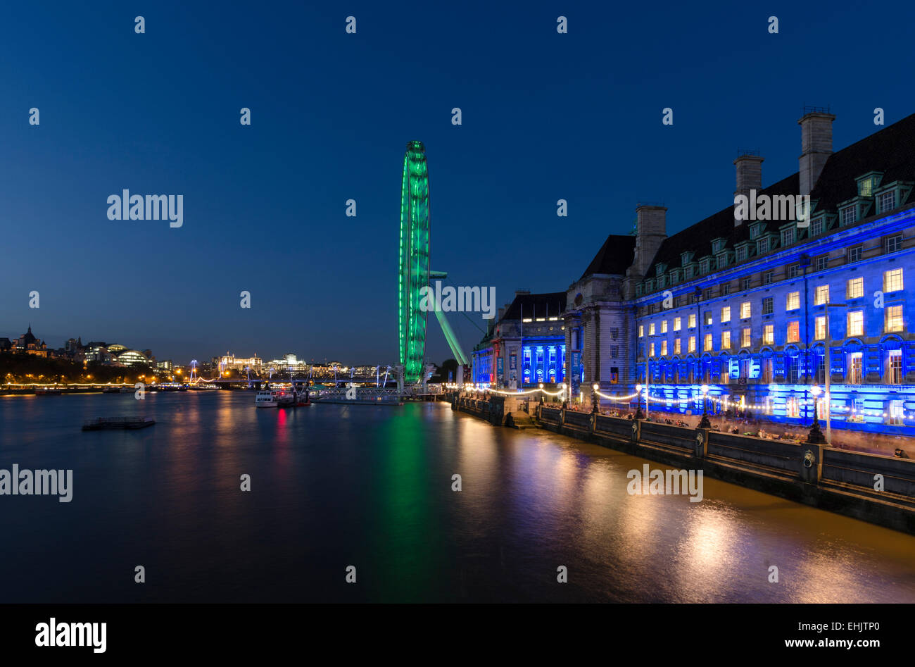 The London Eye and County Hall are illuminated against a nighttime sky ...