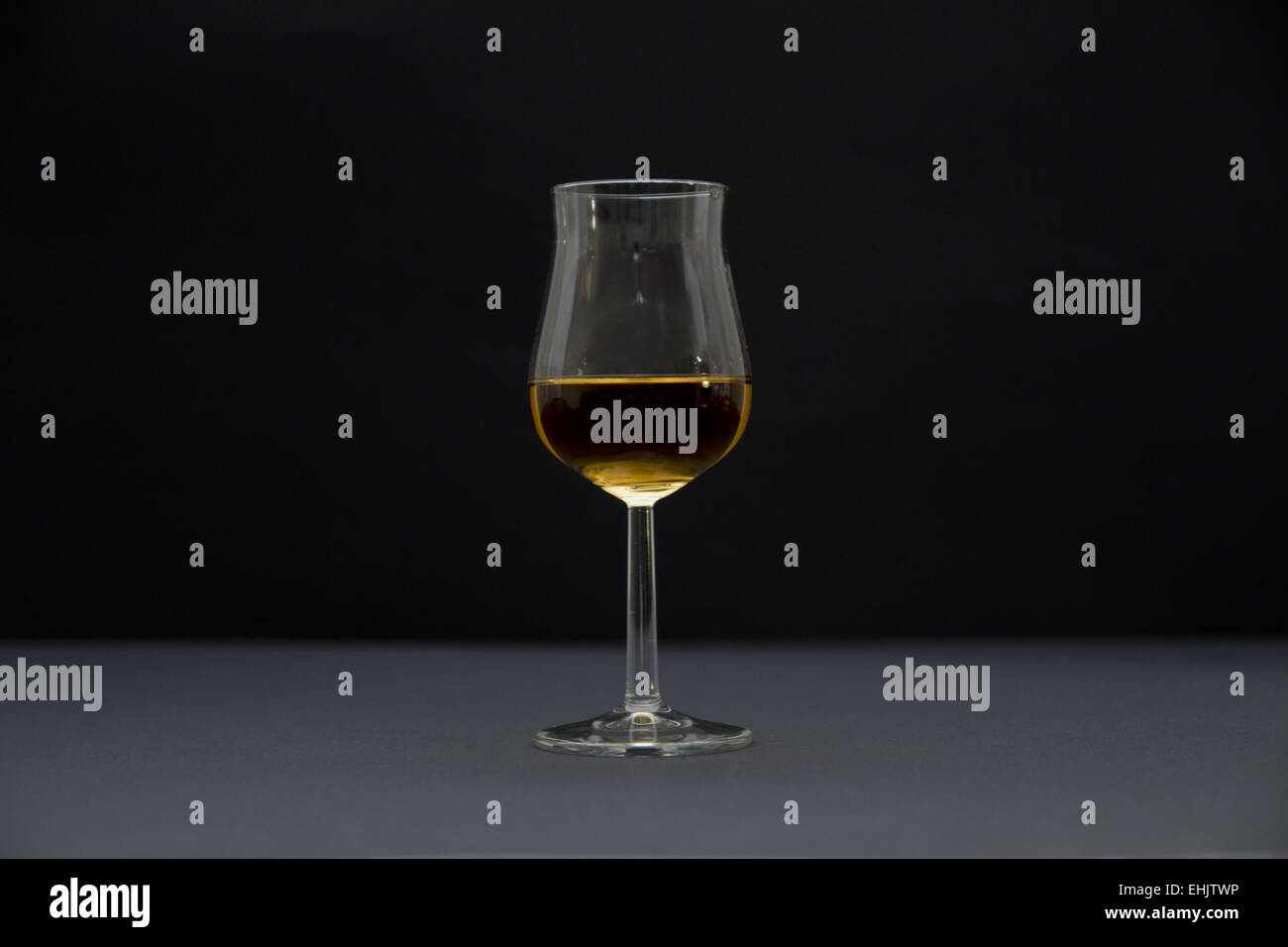 Side view of a glass of cognac. Dark background and shallow depth of ...