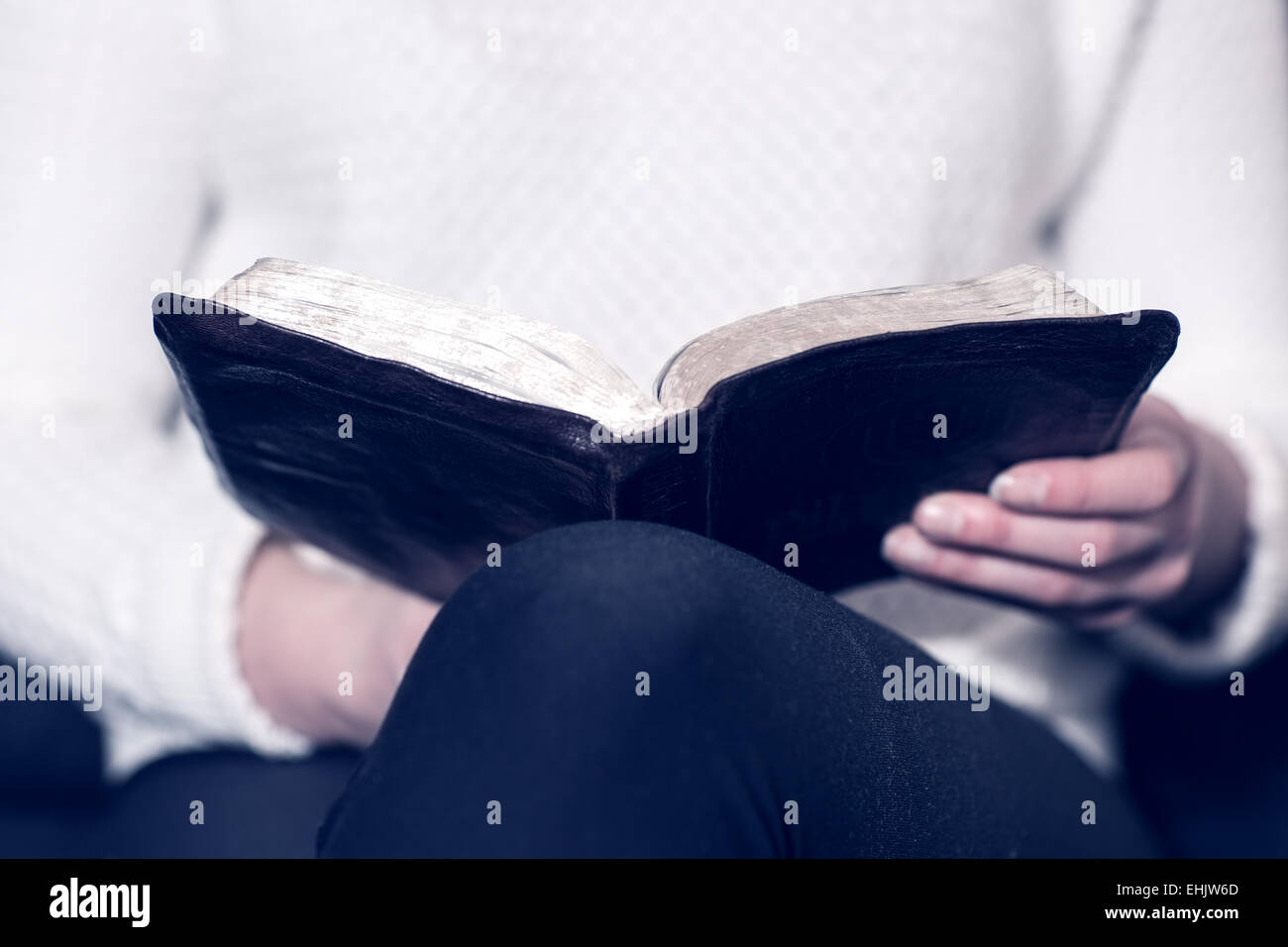 Close-up of a christian woman reading the holy bible. Sitting in sofa ...