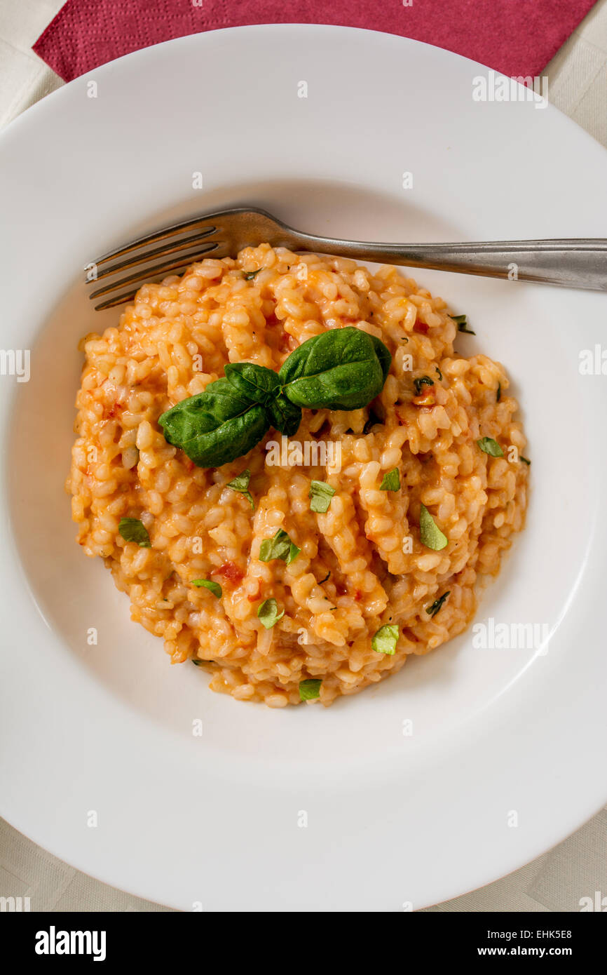 Red risotto with tomato and basil on white plate Stock Photo - Alamy