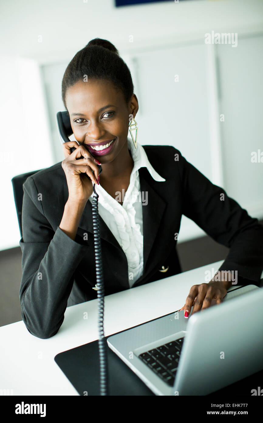 Young african woman in the office with mobile phone Stock Photo - Alamy